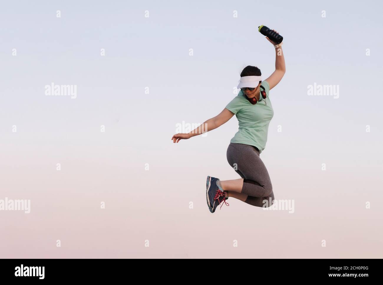 woman jumping while doing sport on a blue background Stock Photo - Alamy