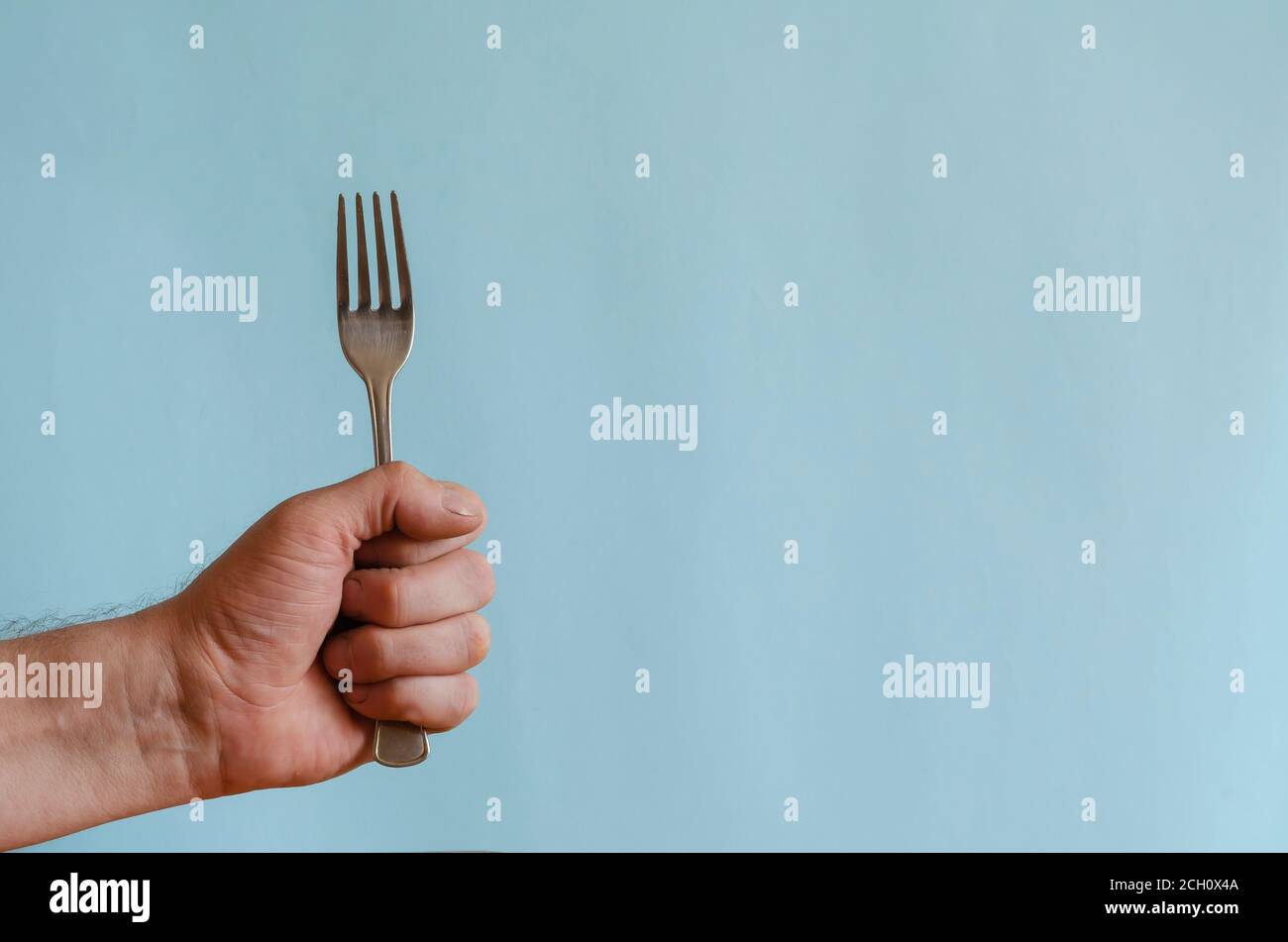 Hand of an adult male holds a metal fork. Stainless steel fork in his ...
