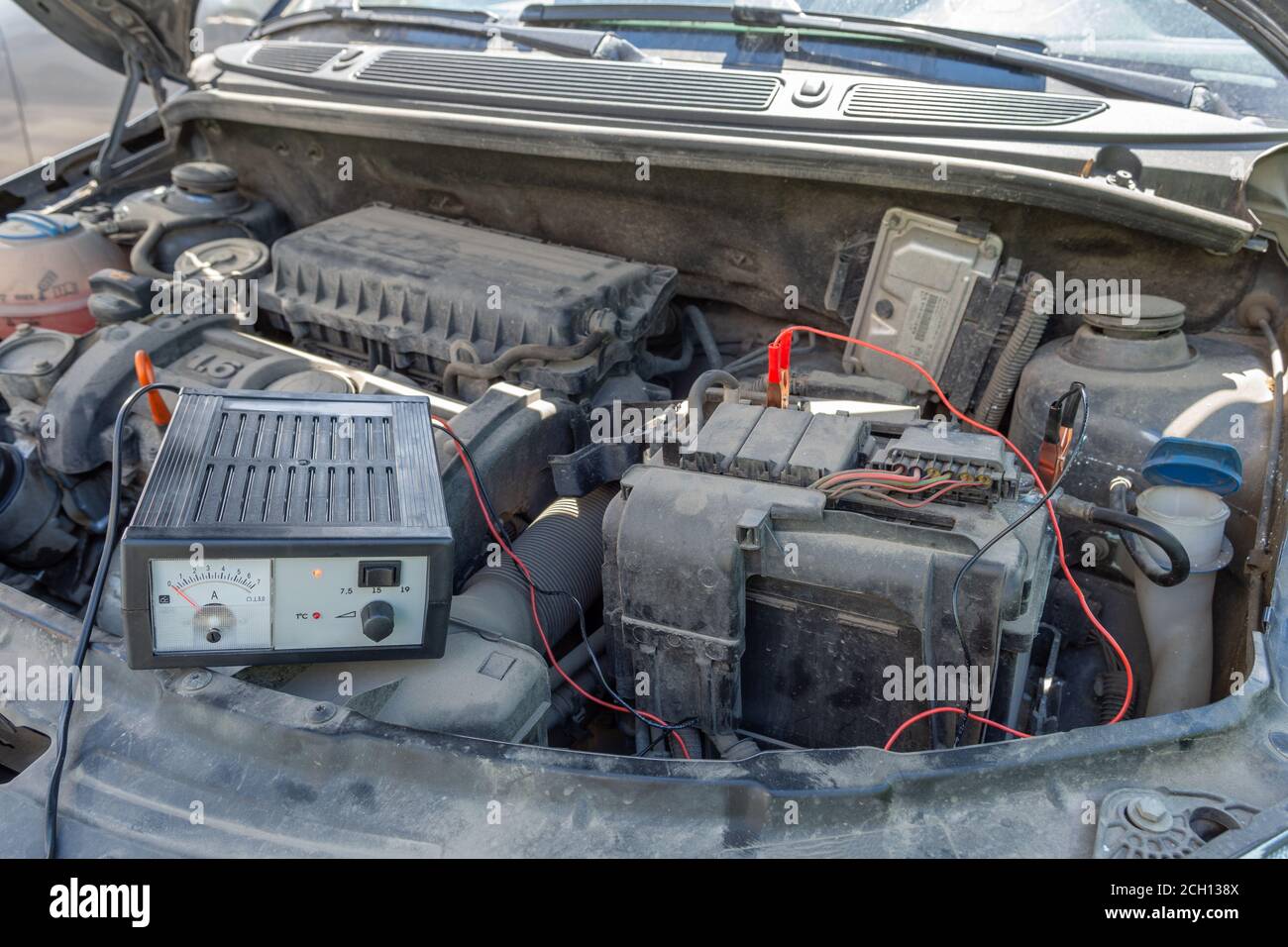 checking voltage of car battery under the open hood of the car ...