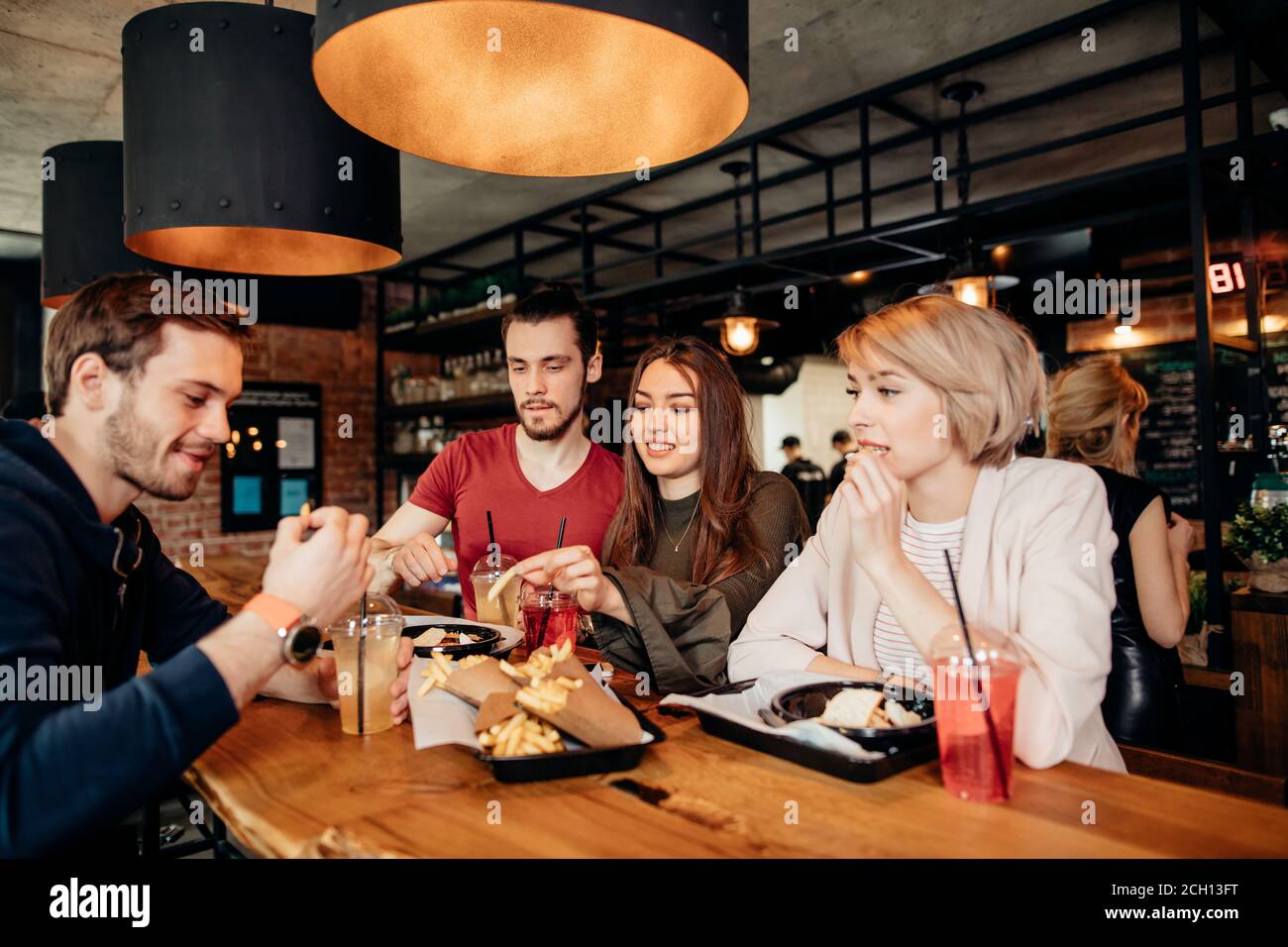 friends eating french fries and hamburgers together at outdoor ...