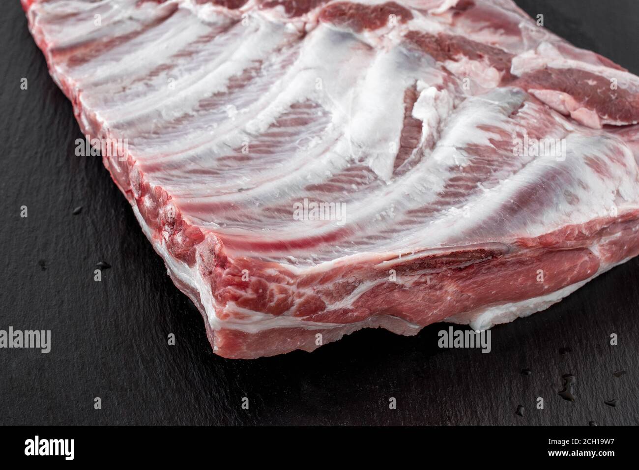 Whole raw pork ribs isolated on dark, black, stone board. spare ribs or ...