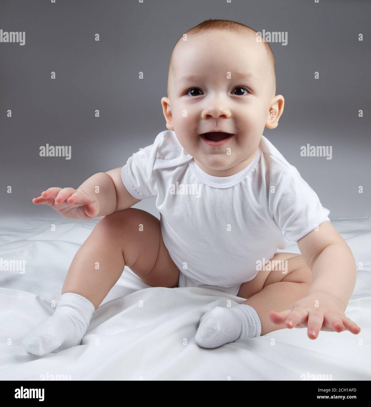 Photo of a ten-month-old smiling baby looking forward on a white ...