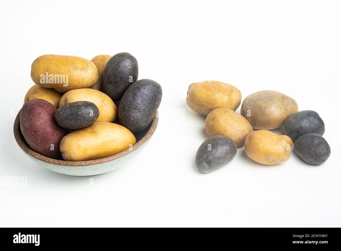 An assorted color raw and fresh potatoes artfully arranged on bowl and ...