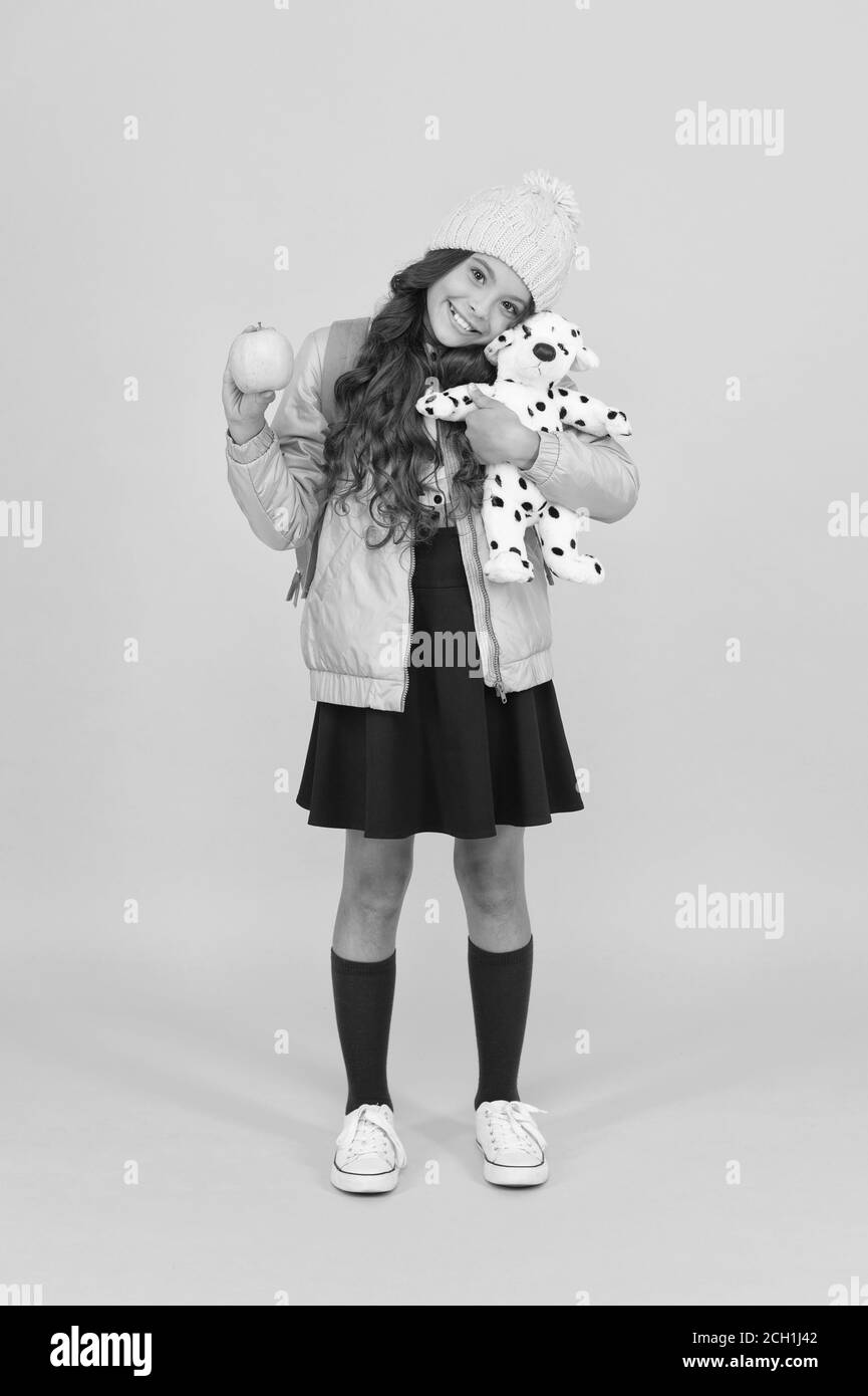 Stay childish. Small child hold soft toy and apple. Little girl enjoy ...