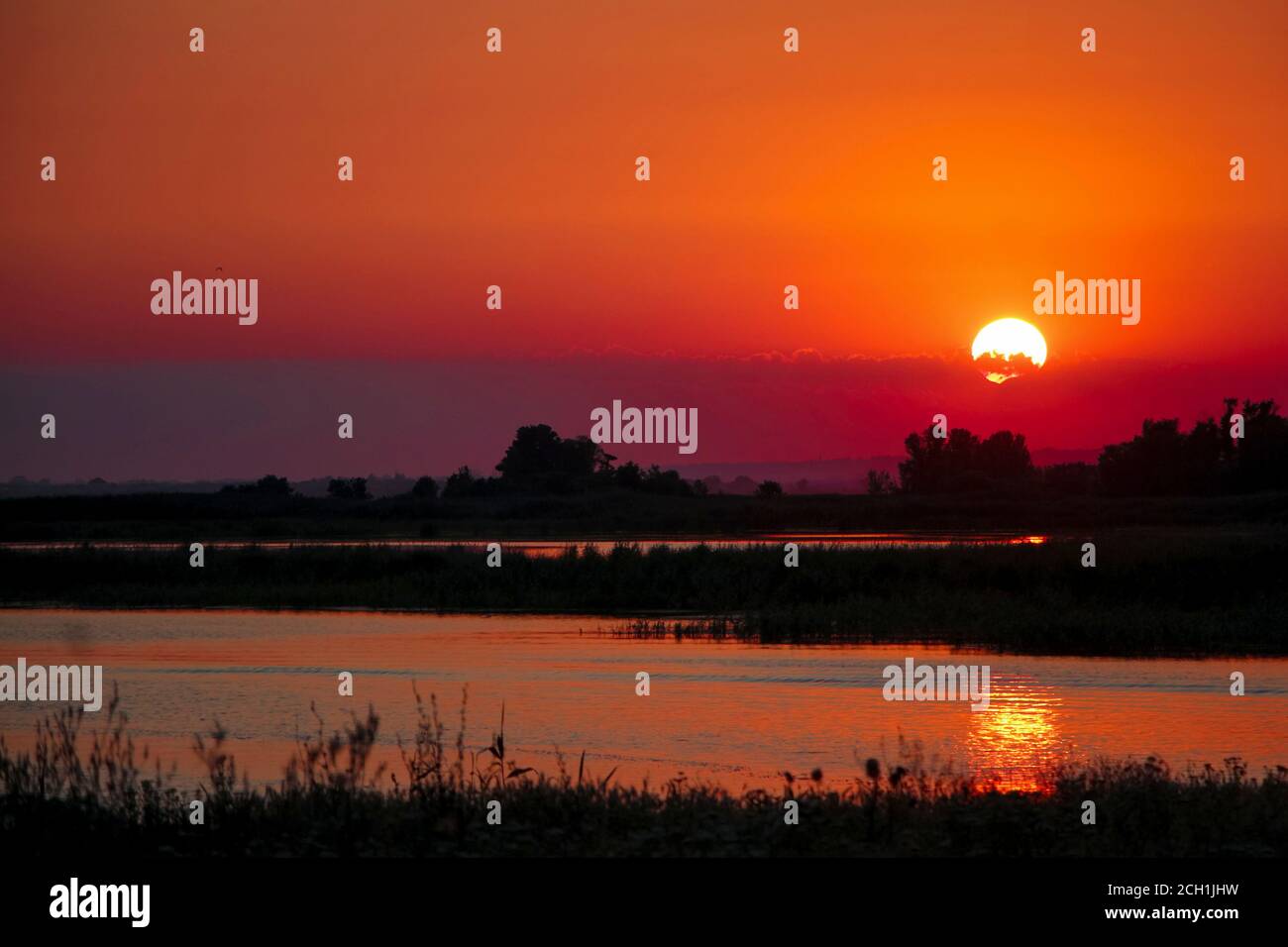 Beautiful red and orange sunset over the river. Golden twillight ...