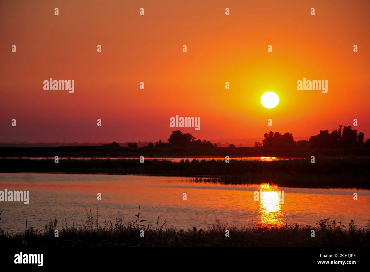 Beautiful red and orange sunset over the river. Golden twillight ...