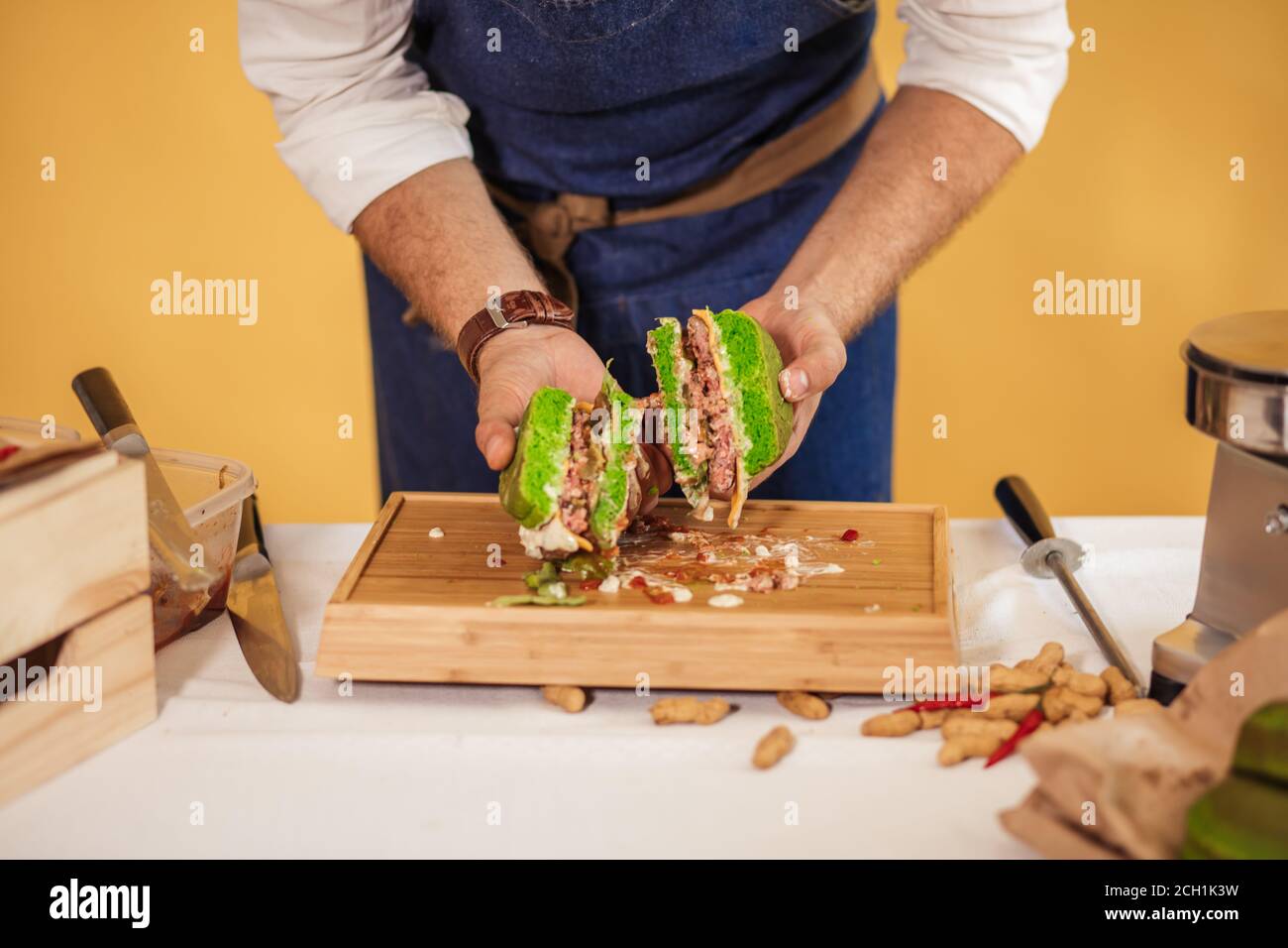 Close up of appetising beef burger. Chef's hands divide into half ...