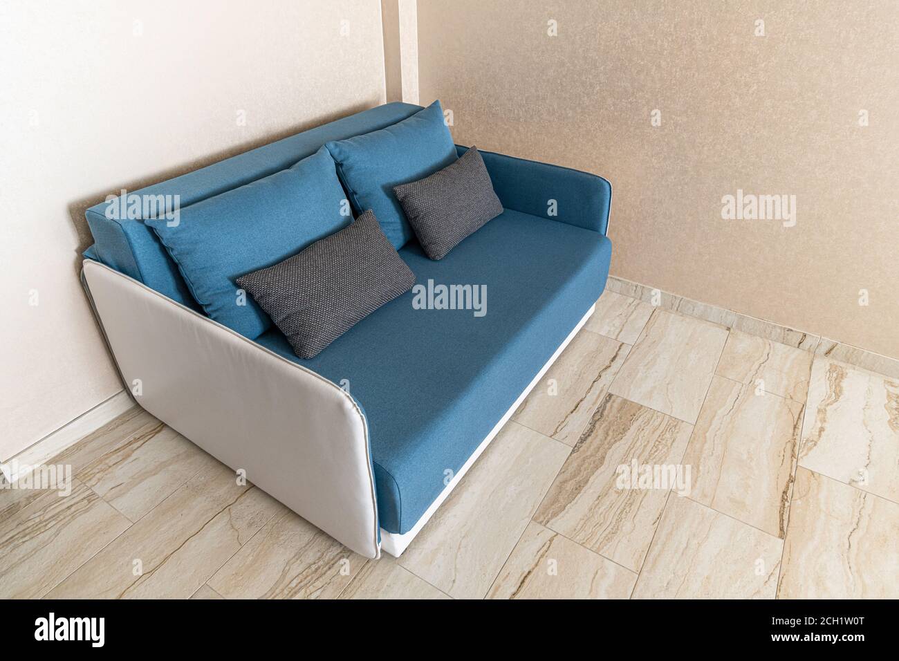 small blue sofa with pillows in the corner of the room Stock Photo - Alamy