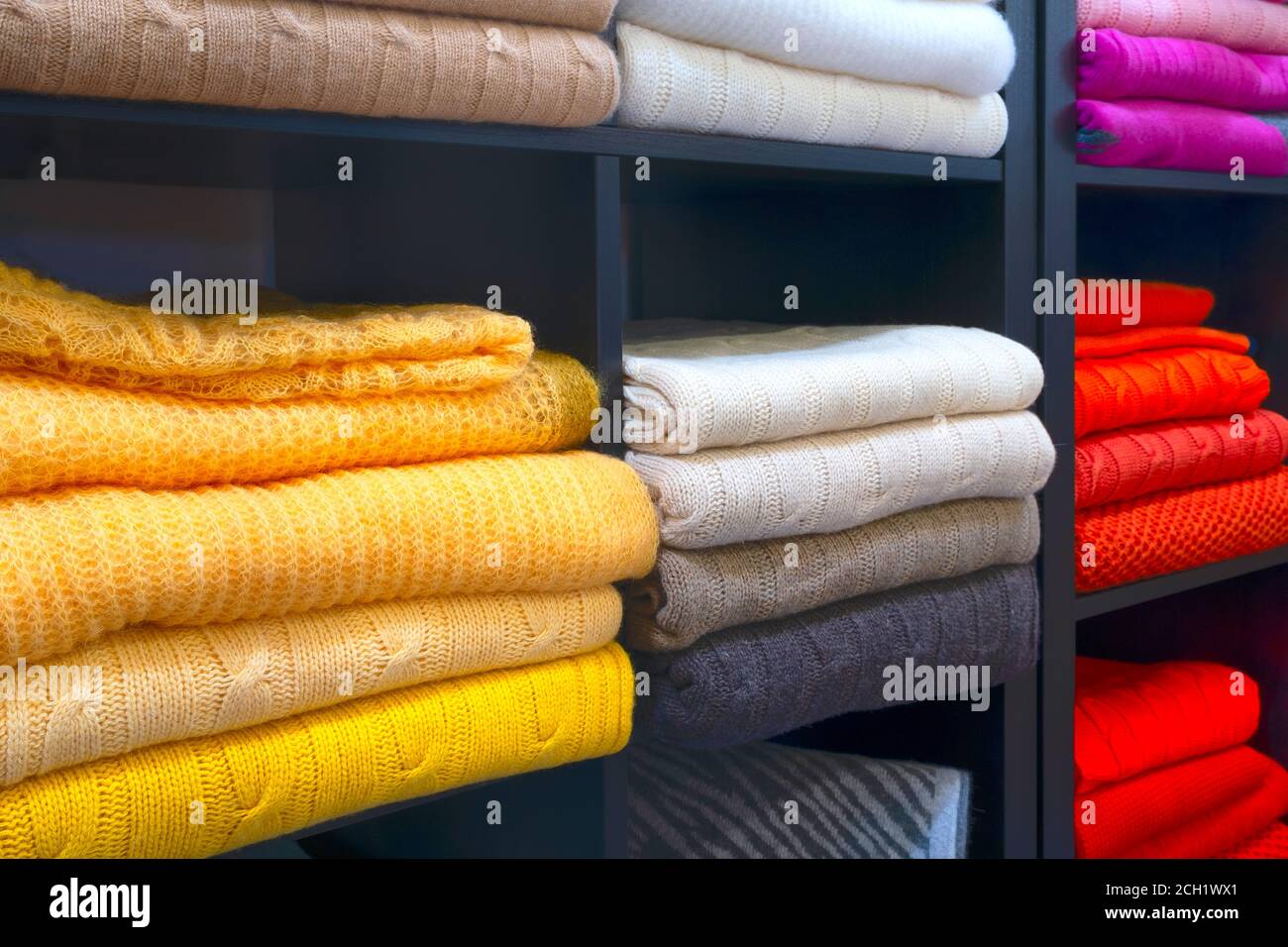 Row of colorful clothes on shelf Stock Photo - Alamy