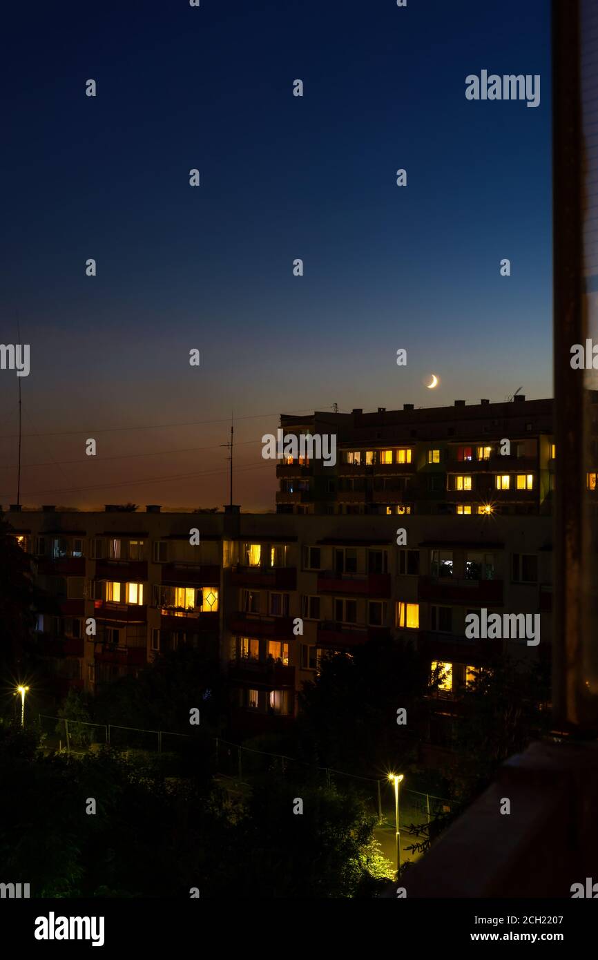 Waxing crescent moon rising over apartment blocks at nightfall, urban ...