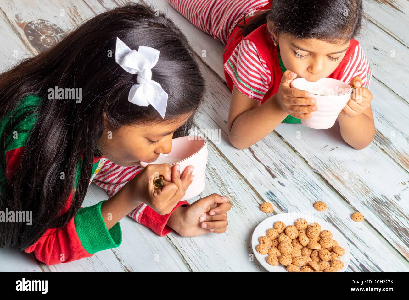 Little sisters eating cookies with milk on Christmas day Stock Photo ...