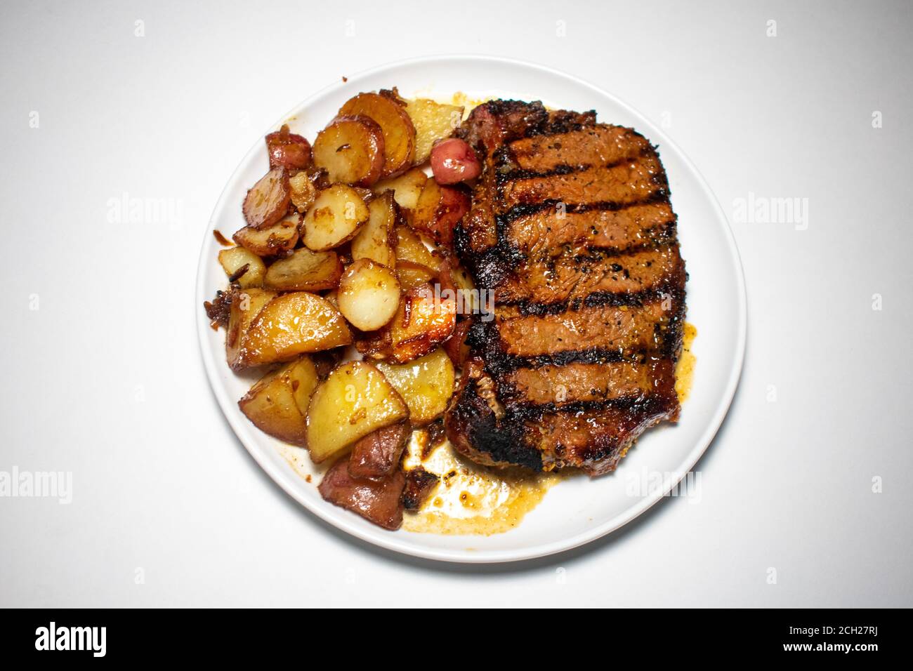 A Perfectly Grilled Steak With Black Grill Lines and Potatoes Plated on ...