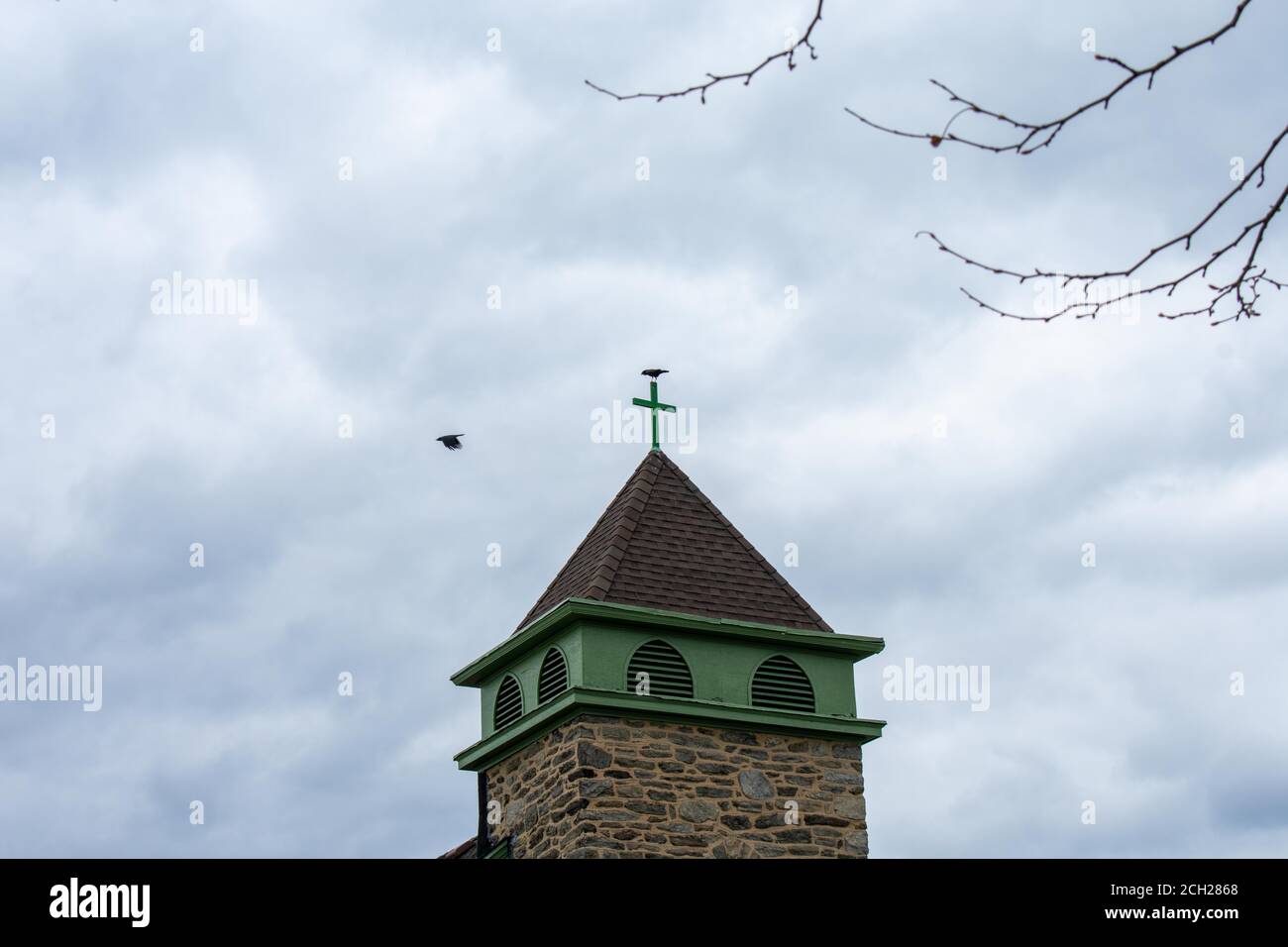 The Tower of a Cobblestone Church With a Cross on Top on a Cloudy ...