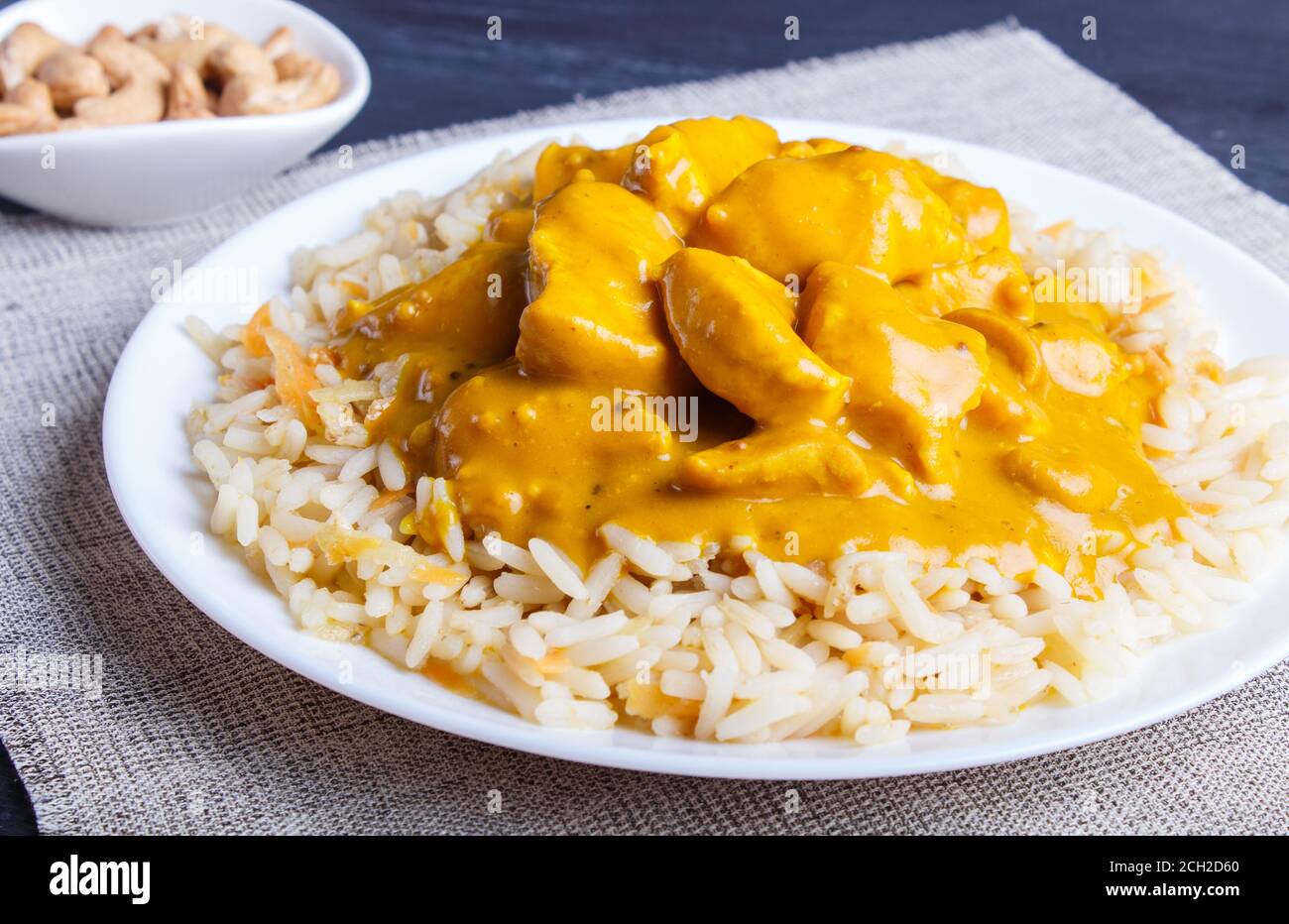 Rice with chicken curry sauce with cashew on black wooden background ...
