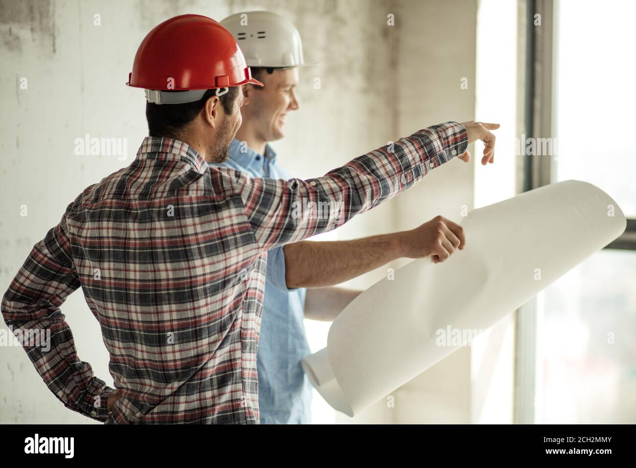 two attractive laughing builders are talking about the construction of ...