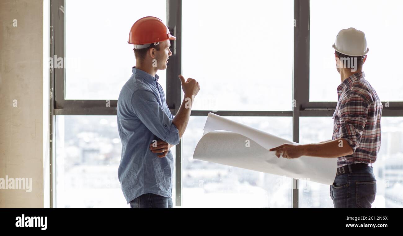 construction worker is looking at the street while his co-worker is ...