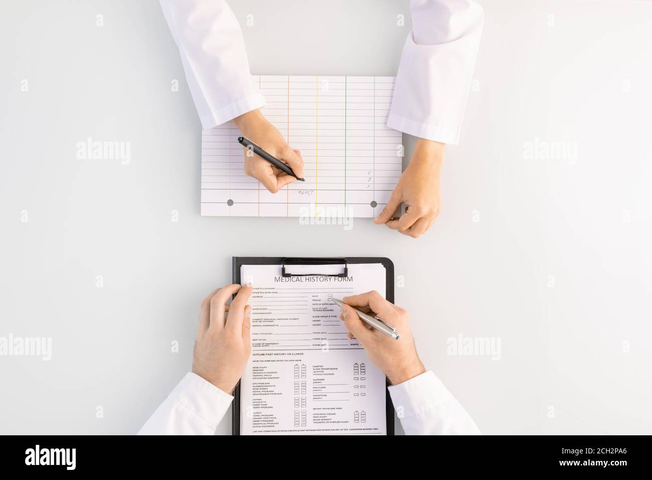 Overview of hands of doctor filling in medical history form with nurse ...