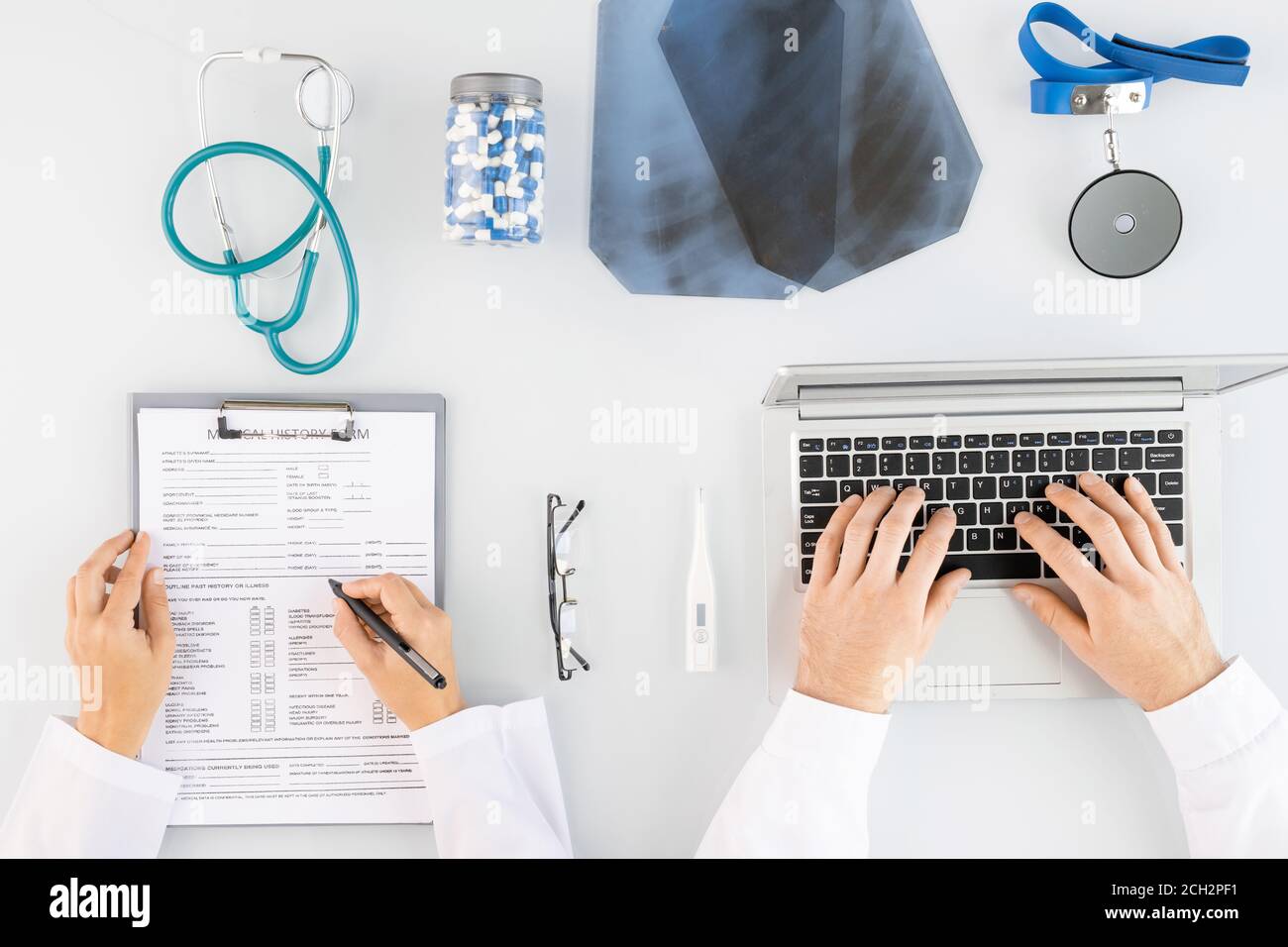 Top view of hands of young doctors in whitecoats making medical notes ...