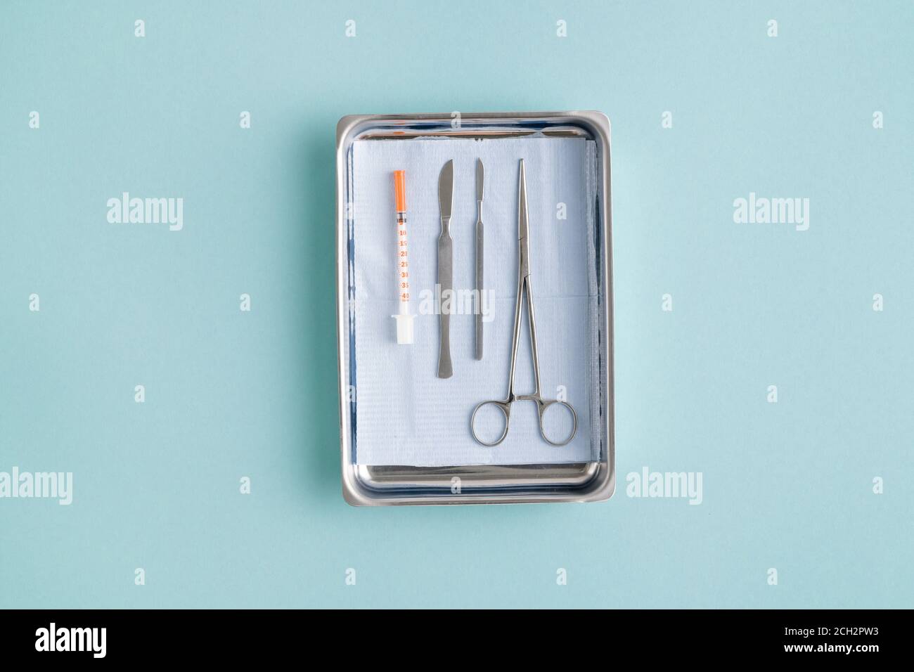 Flatlay of medical bowl with surgical instruments and syringe with ...