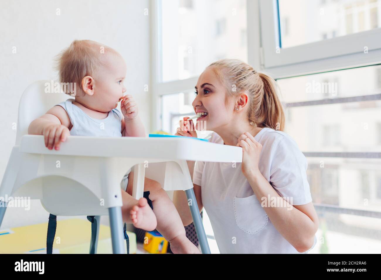 Mother feeding little baby with fruits at home. Family eating together ...