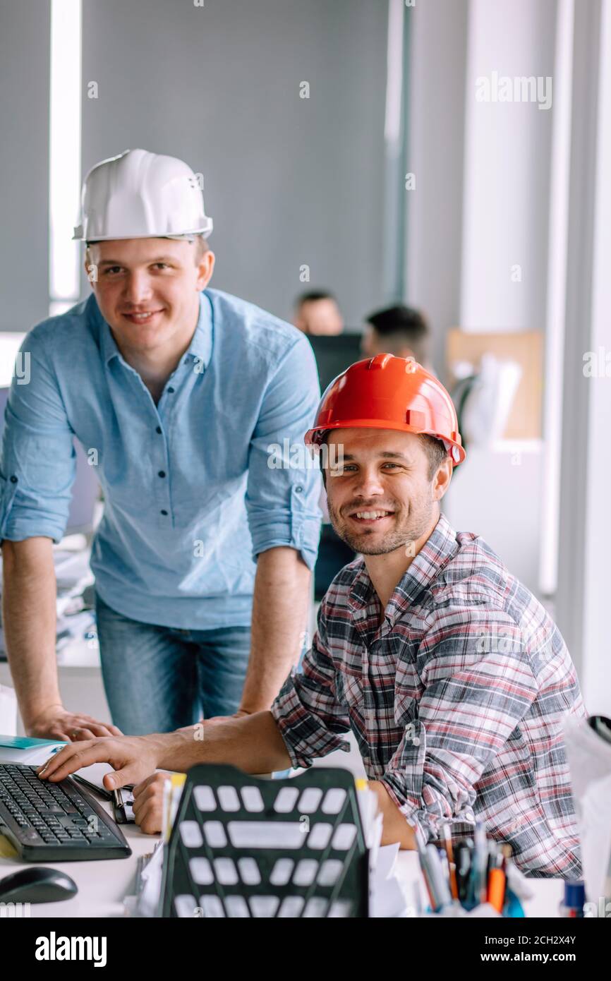 successful positive engineers in hardhats are looking at the camera at ...