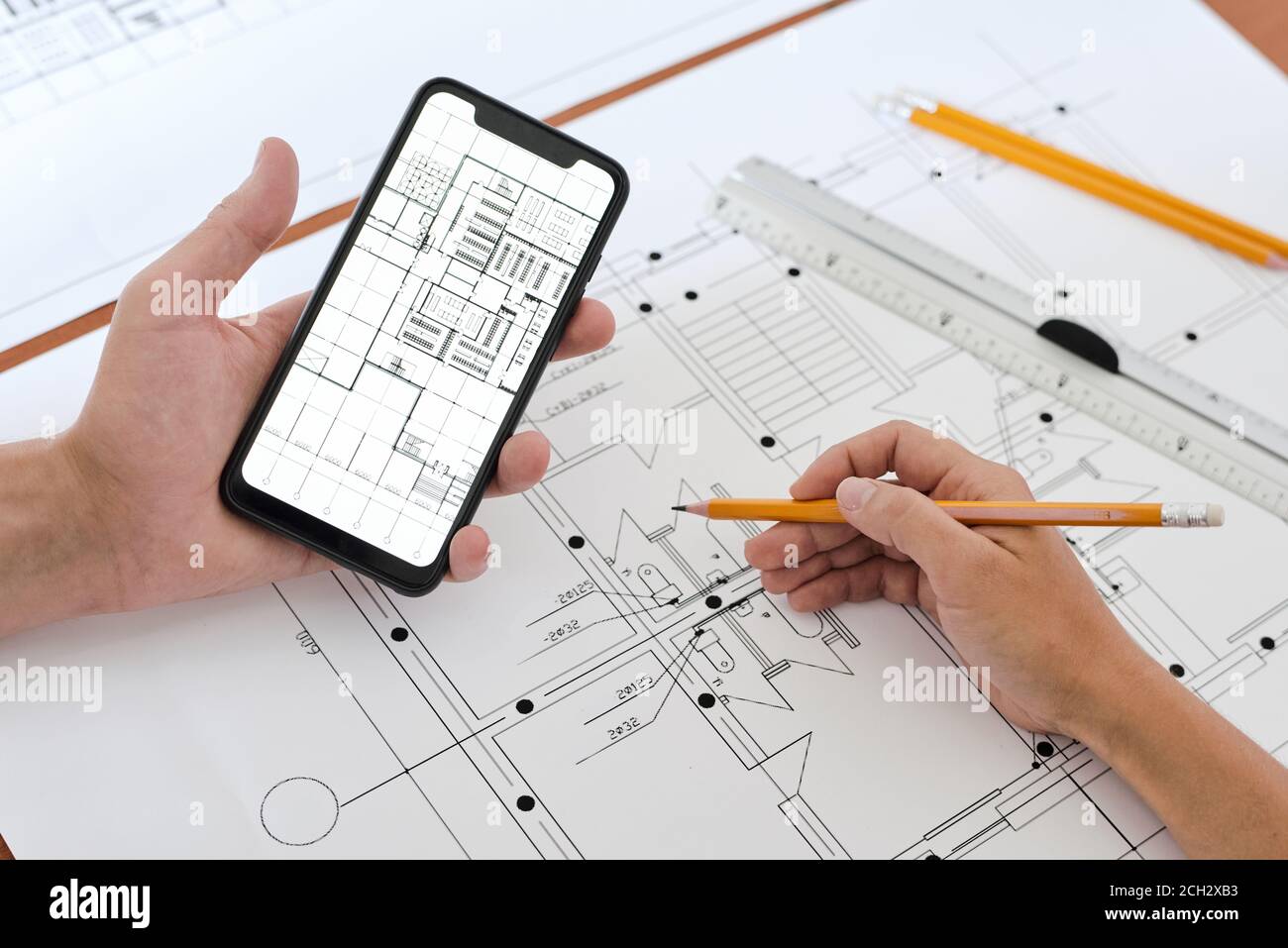 Hands of young busy engineer or architect with pencil over sketch of ...