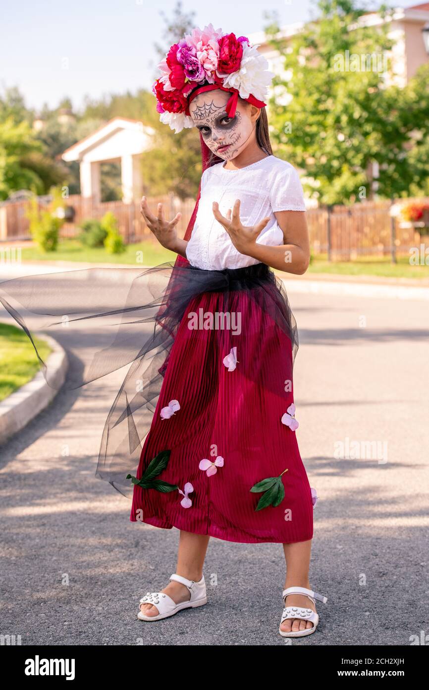 Schoolgirl with painted face in halloween costume looking with sulky ...