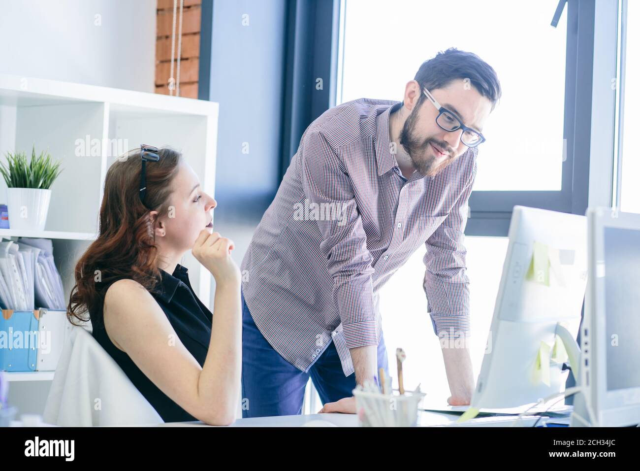 serious woman and unserious man in the loft room in front of computer ...