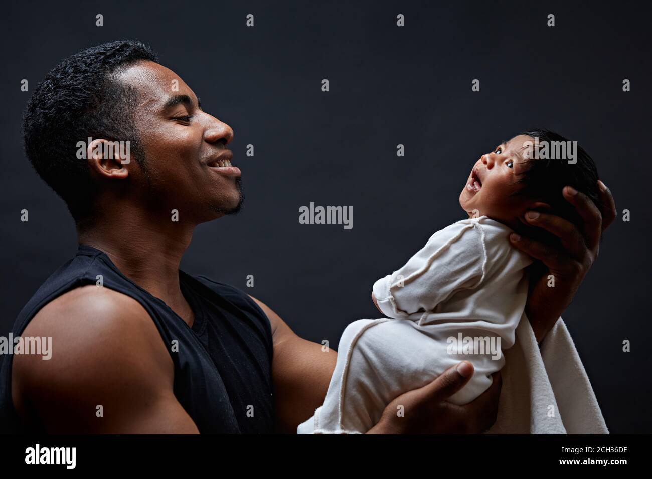 afro handsome man is looking at the baby who is crying. close up side ...