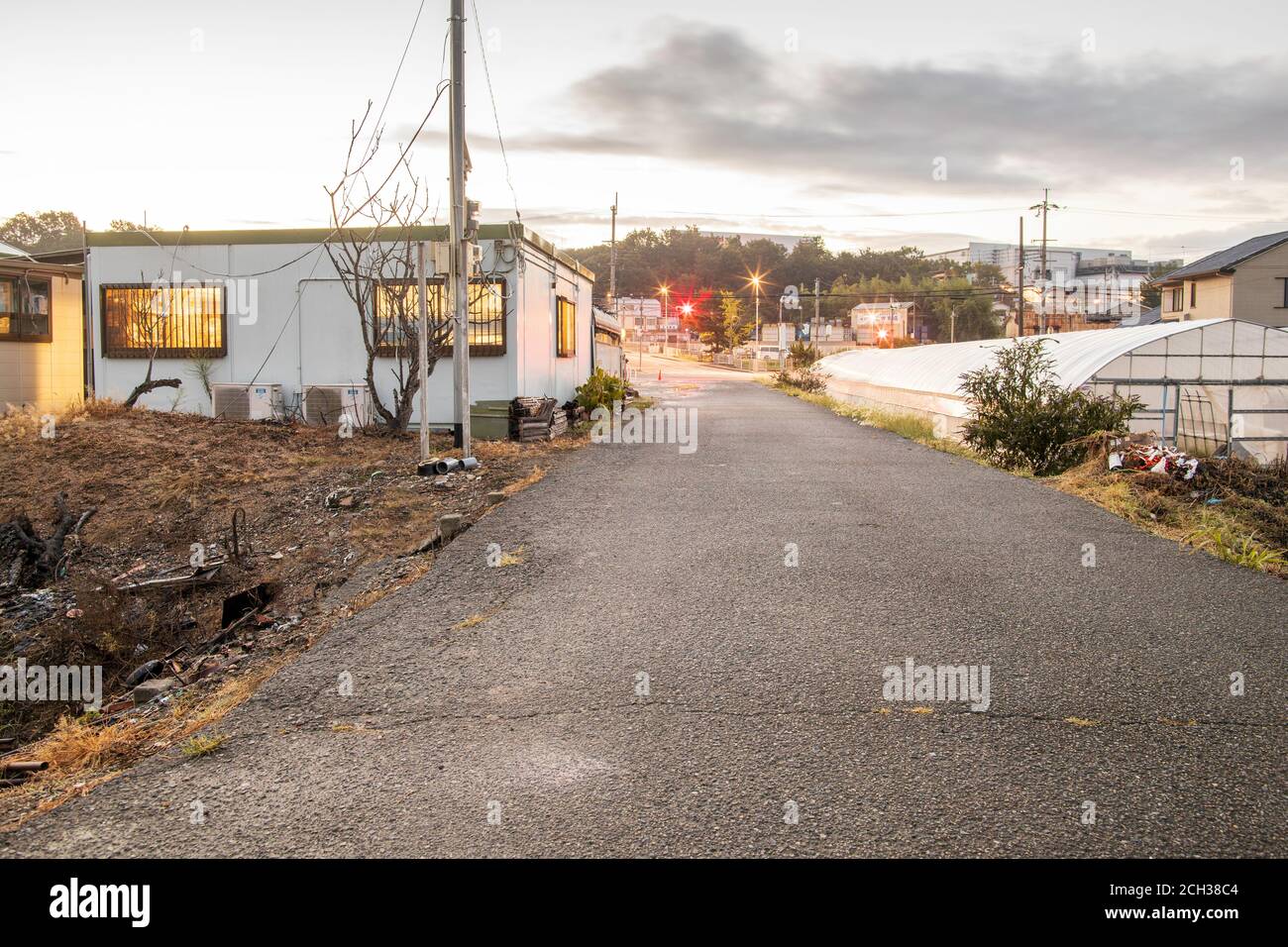 Empty road between greenhouse and small building to empty intersection ...