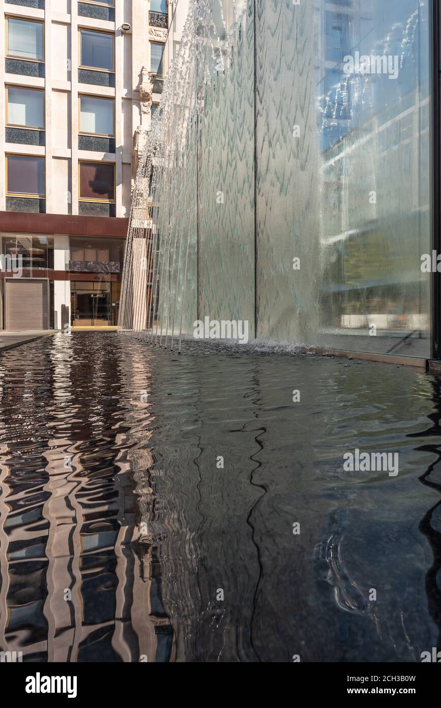 Modern fountain with water splashes on a huge glass window ...