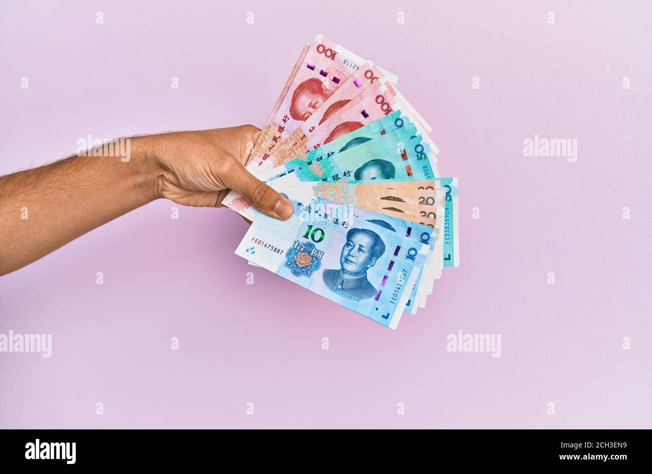 Hispanic hand holding bunch of chinese yuan banknotes over isolated ...