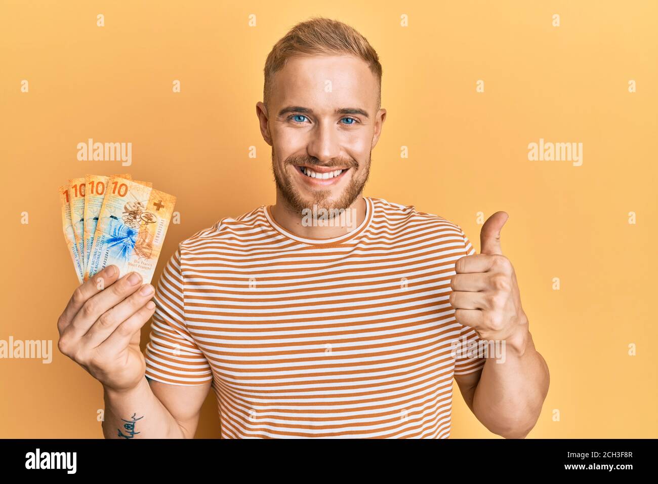 Young caucasian man holding swiss franc banknotes smiling happy and ...