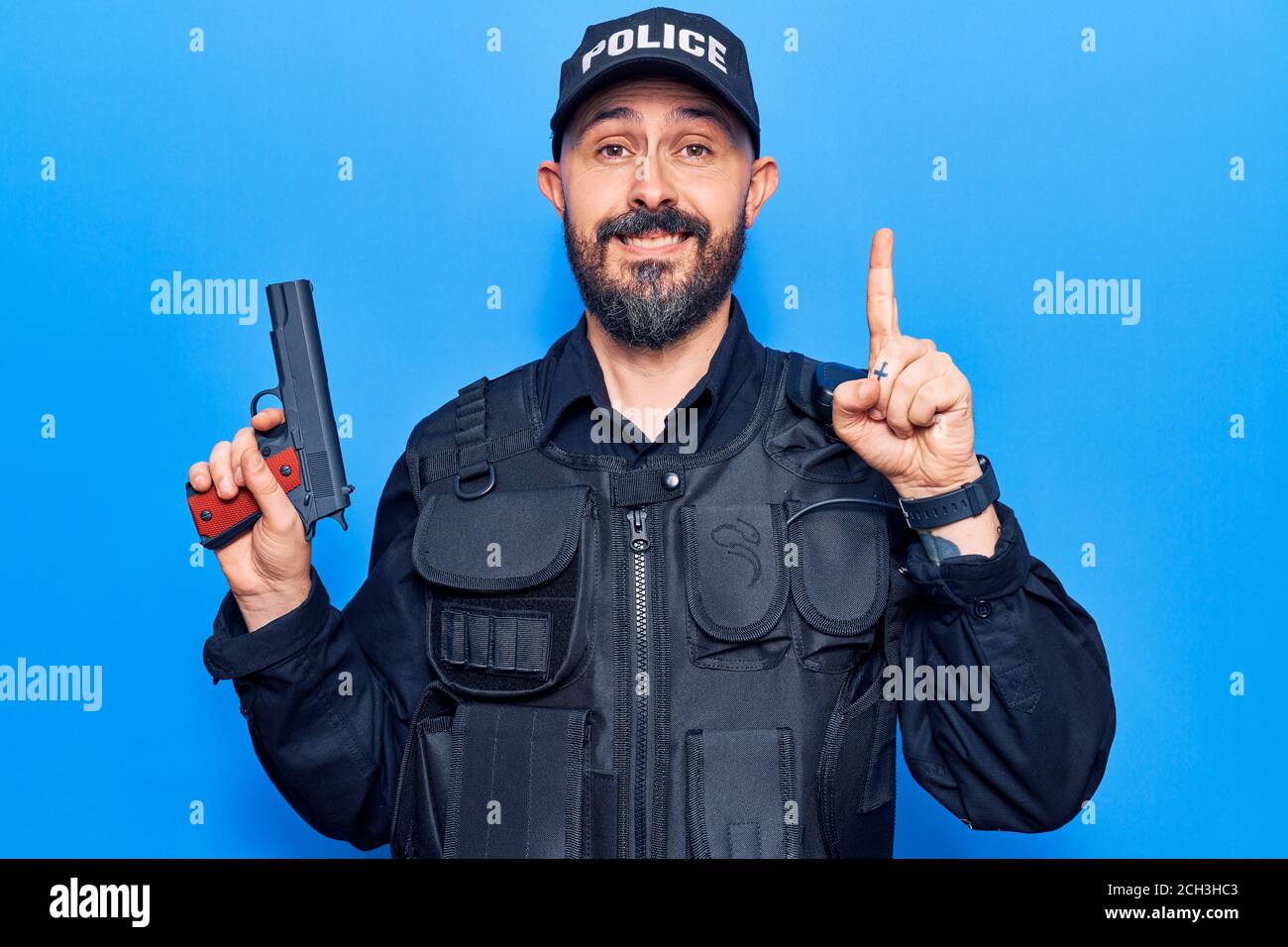 Young handsome man wearing police uniform holding gun smiling with an ...