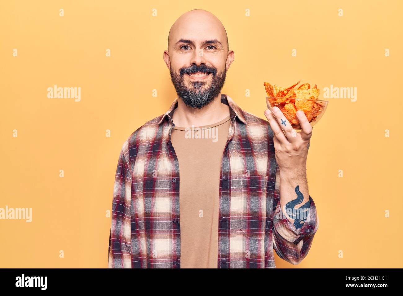Young handsome man holding nachos potato chips looking positive and ...