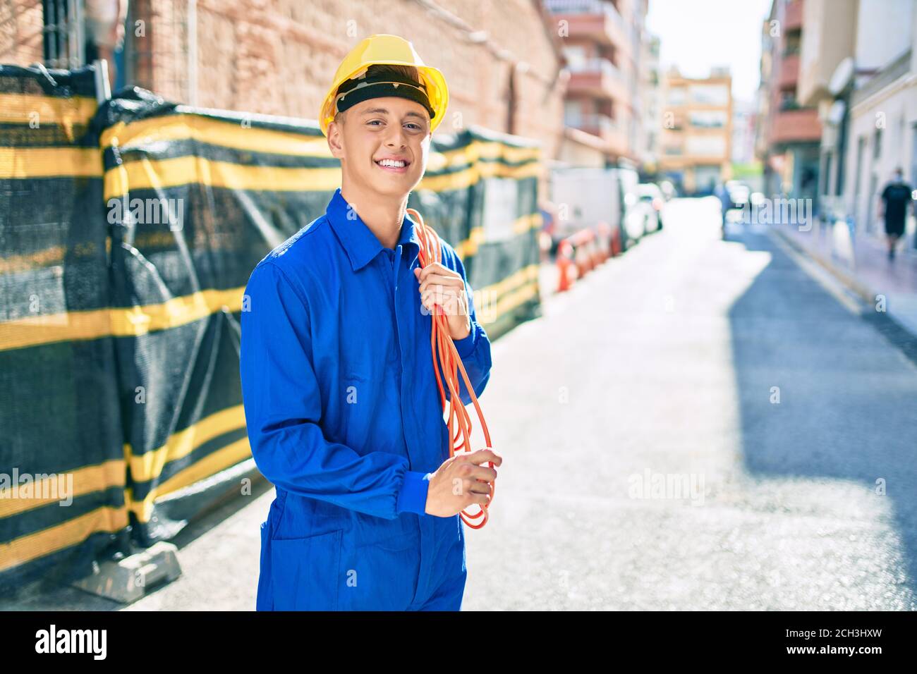 Young hispanic workman smiling happy holding electrical cable at street ...