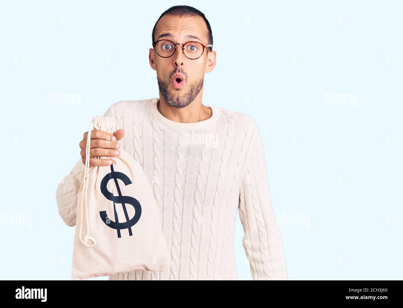 Young handsome man holding money bag with dollar symbol scared and ...