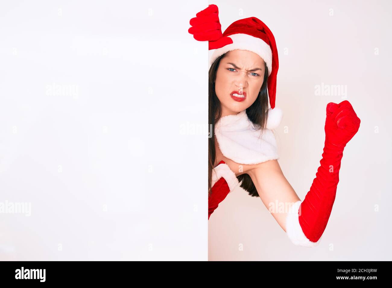 Young woman wearing santa claus costume holding blank empty banner ...