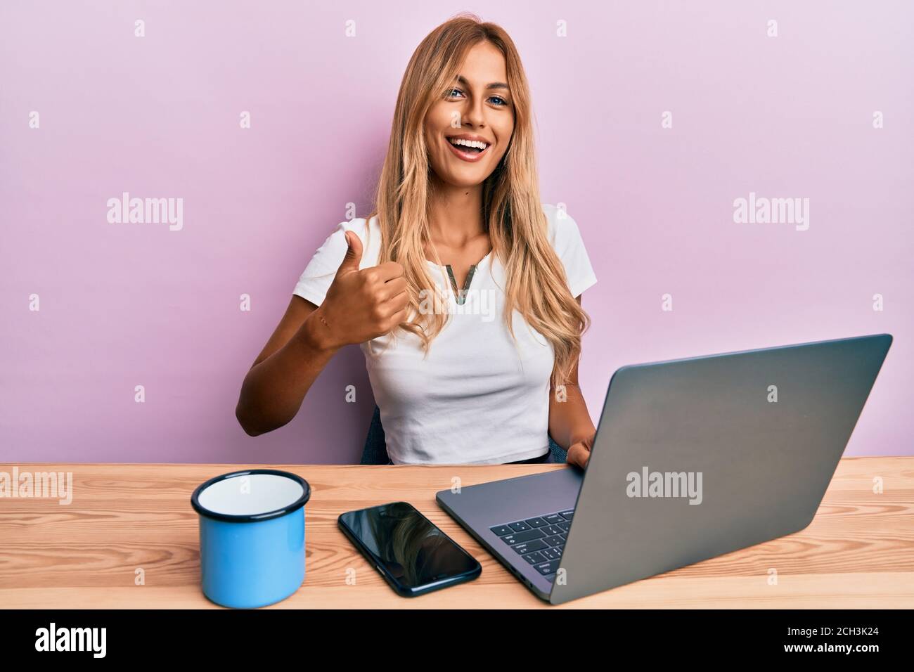 Beautiful blonde young woman working using computer laptop smiling ...
