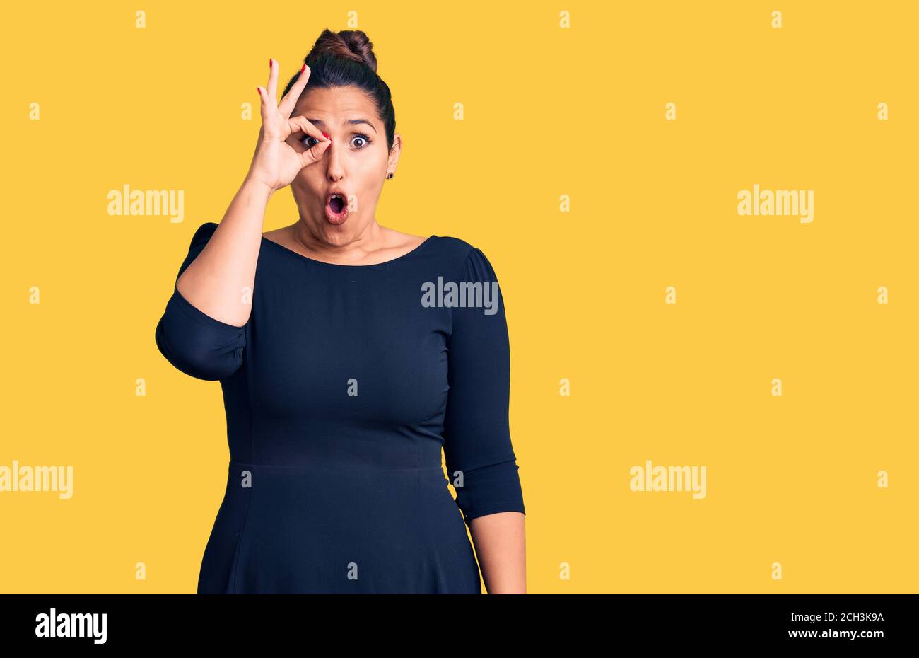 Young beautiful brunette woman wearing casual dress doing ok gesture ...