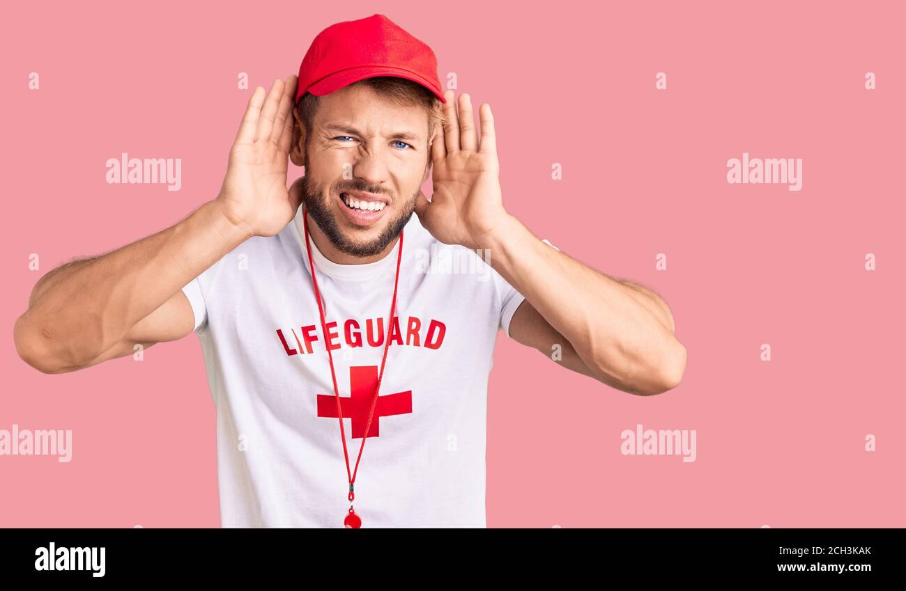 Young caucasian man wearing lifeguard t shirt holding whistle trying to ...