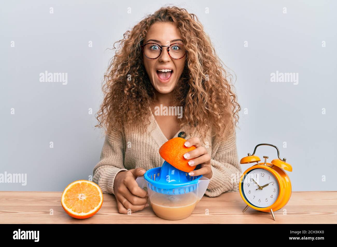 Beautiful caucasian teenager girl making orange juice for breakfast ...