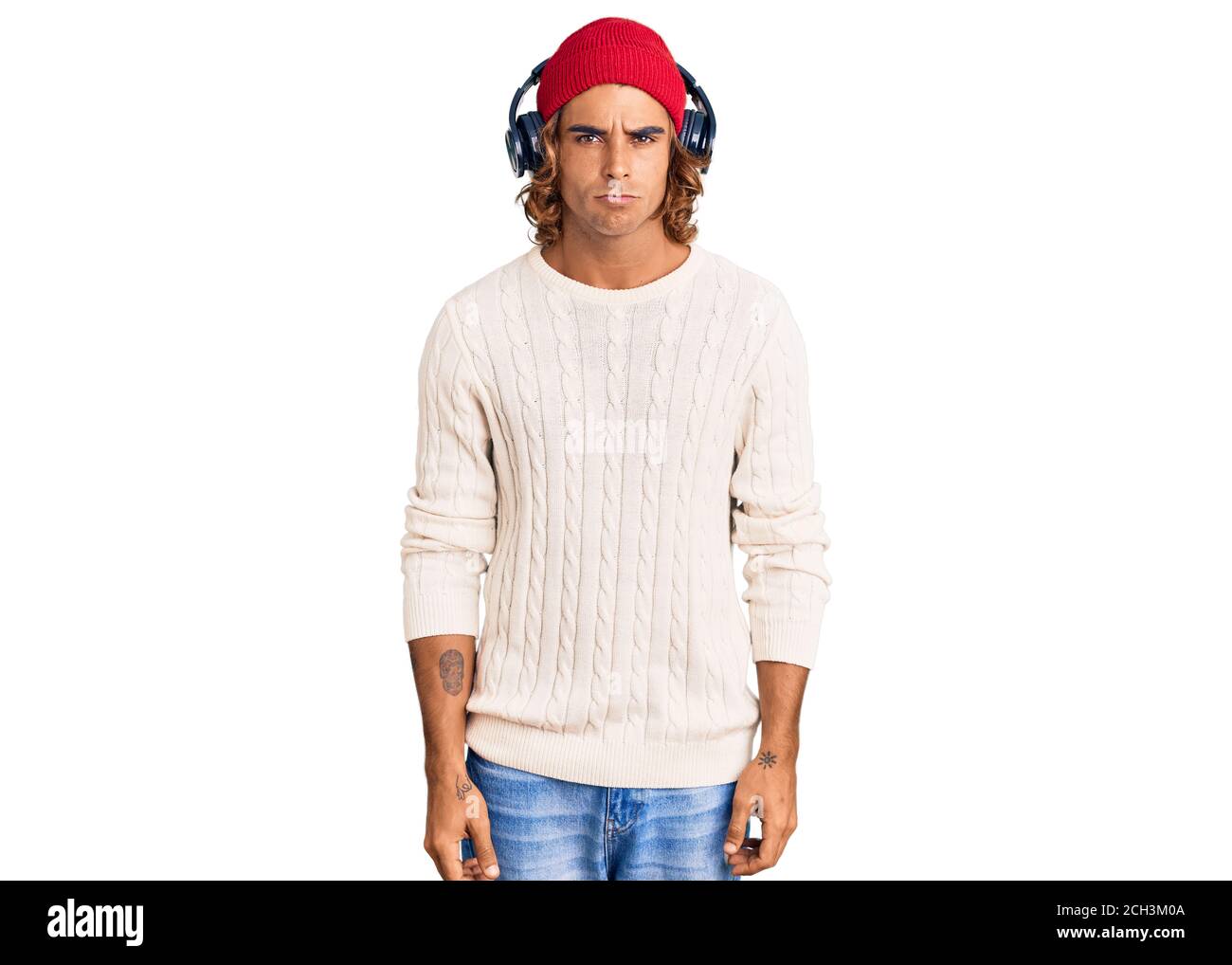 Young hispanic man listening to music using headphones skeptic and ...