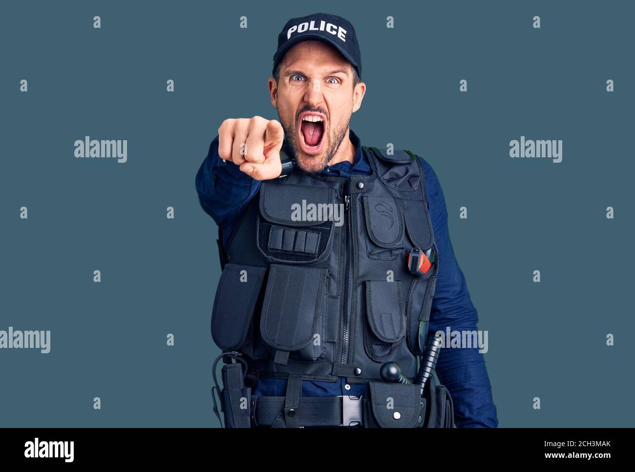 Young handsome man wearing police uniform pointing displeased and ...