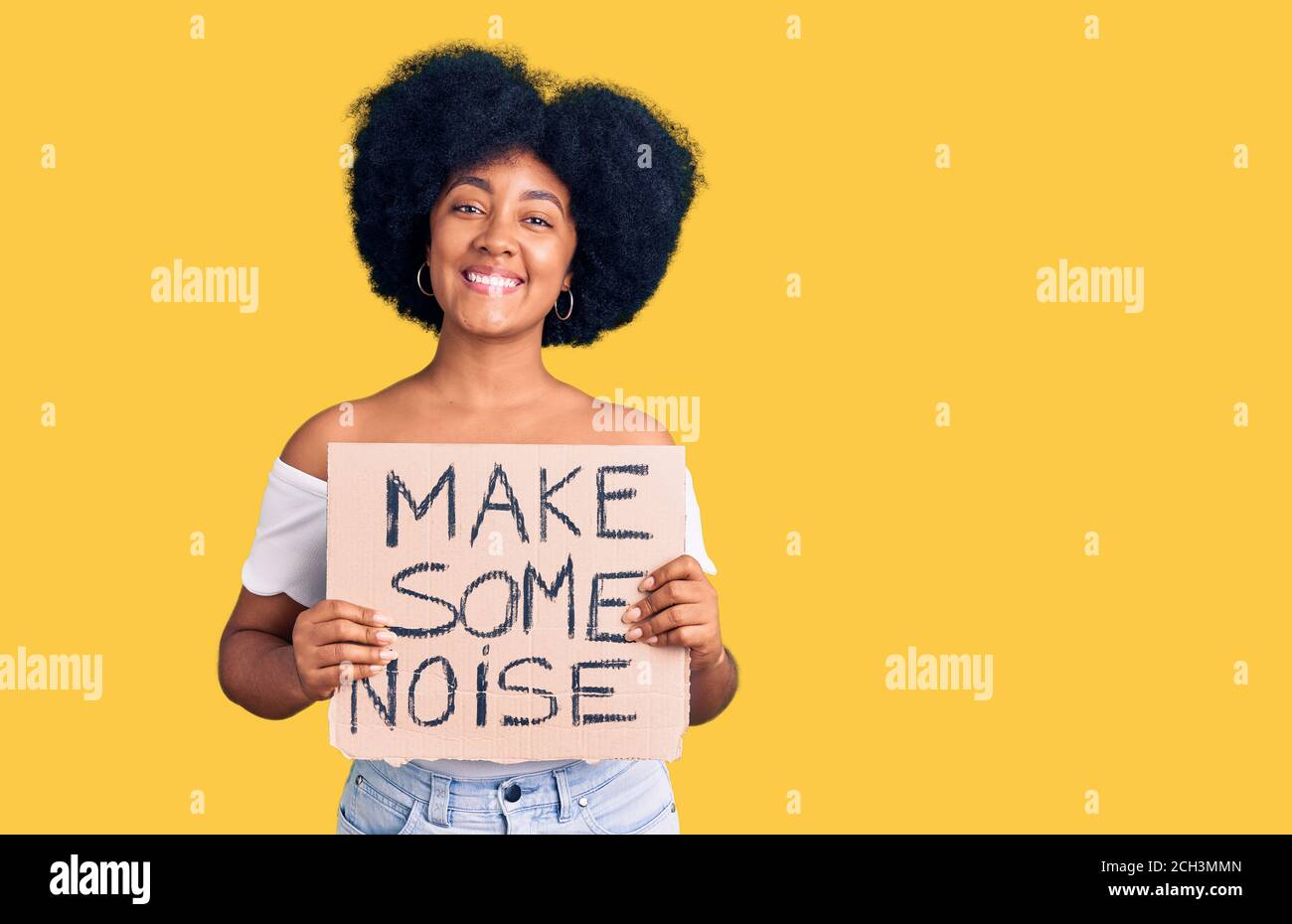 Young african american girl holding make some noise banner looking ...