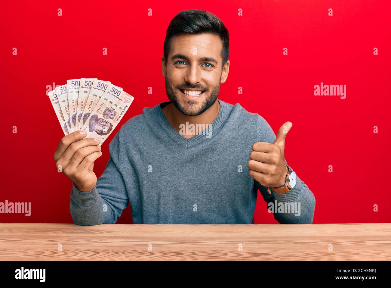 Handsome hispanic man holding mexican pesos smiling happy and positive ...