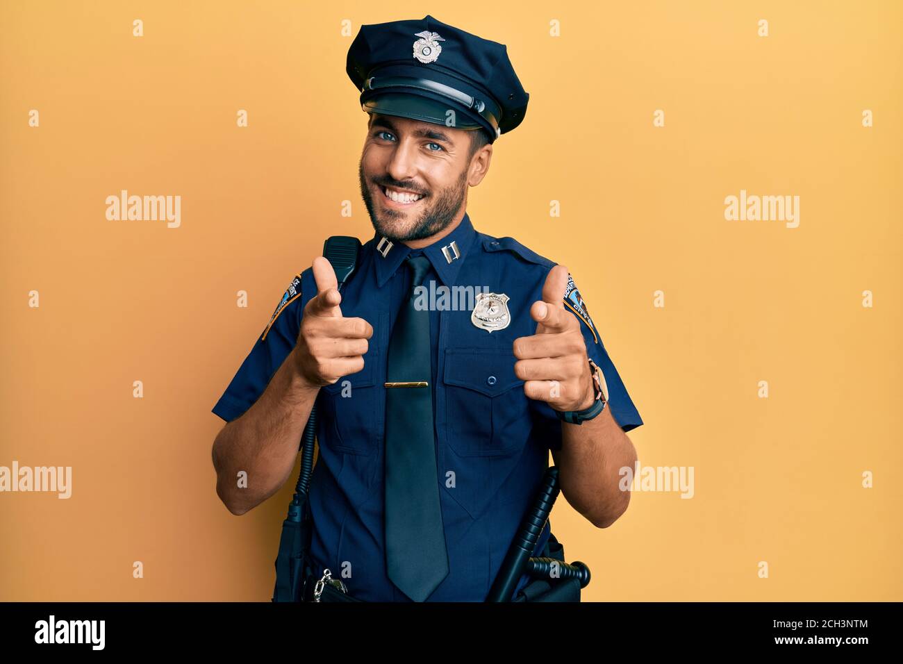 Handsome hispanic man wearing police uniform pointing fingers to camera ...