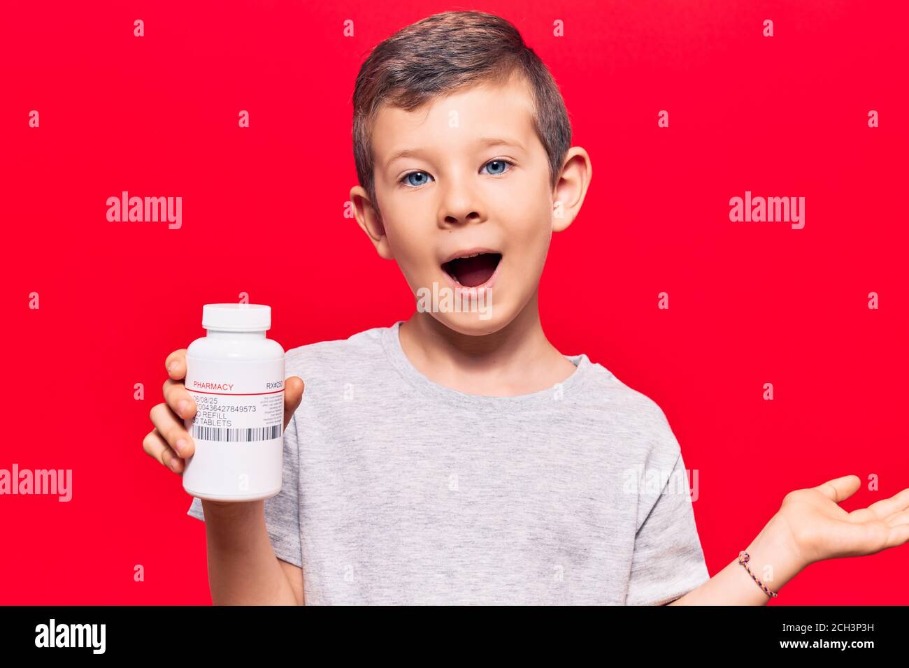 Cute blond kid holding pills celebrating achievement with happy smile ...