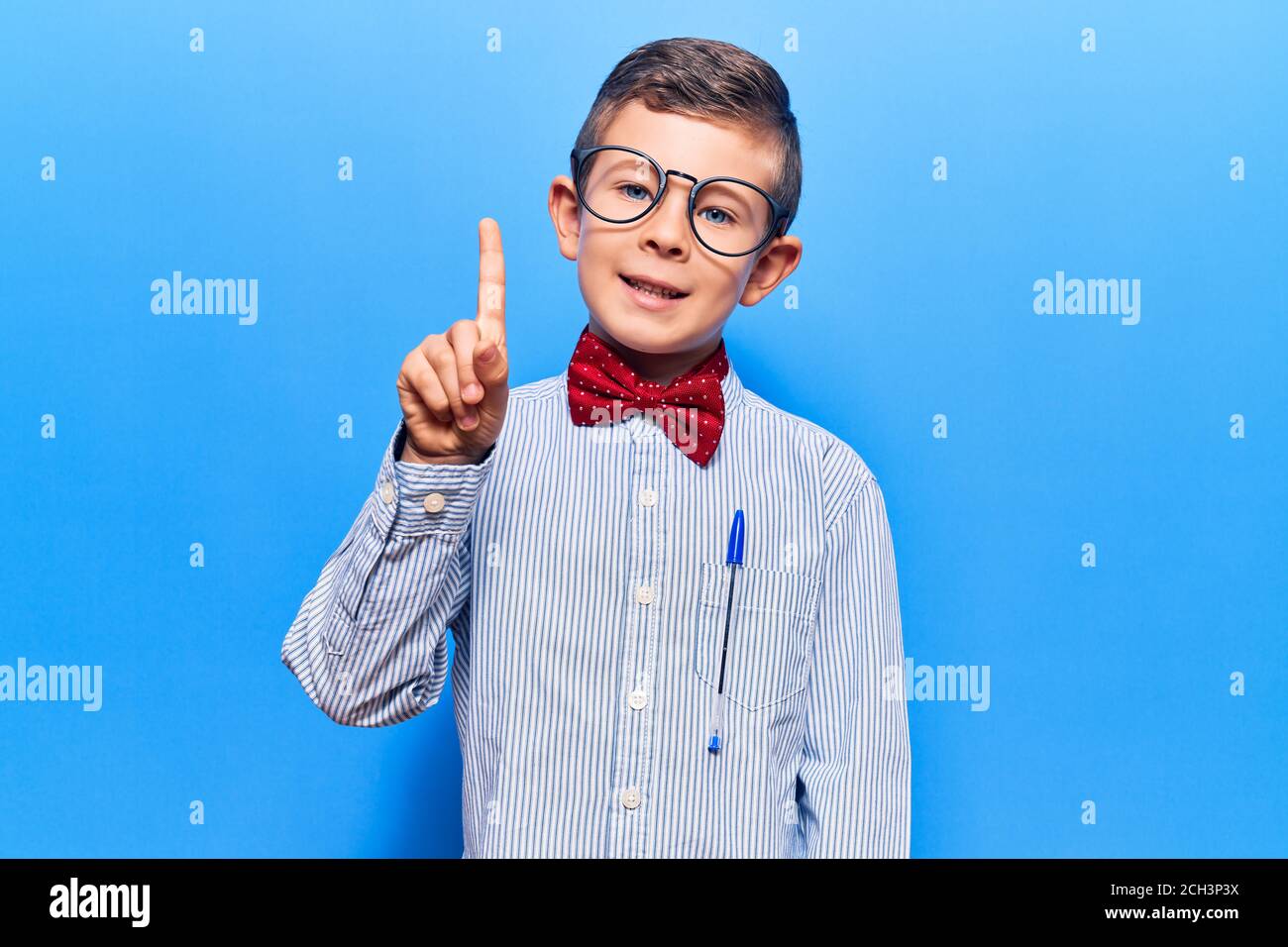 Cute blond kid wearing nerd bow tie and glasses showing and pointing up ...