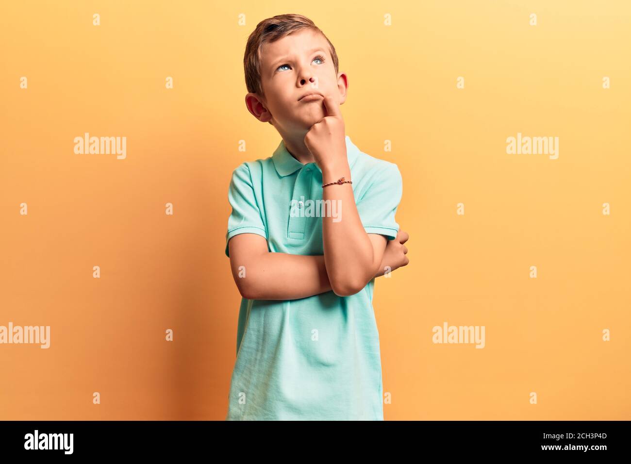 Cute blond kid wearing casual clothes thinking concentrated about doubt ...